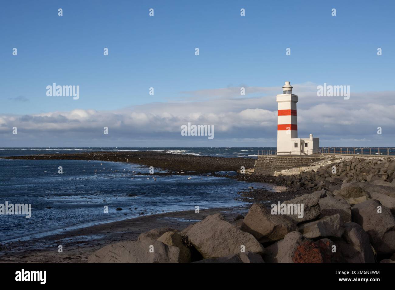 White lighthouse with red stripes on the coast of North Atlantic Ocean ...