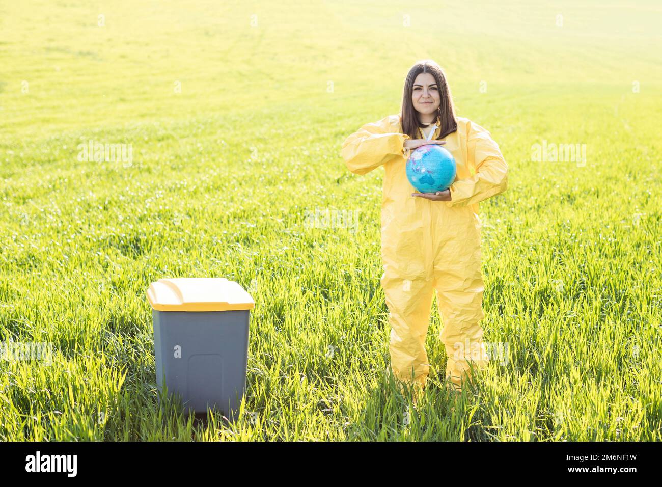 A woman in a yellow protective suit stands in the middle of a green ...
