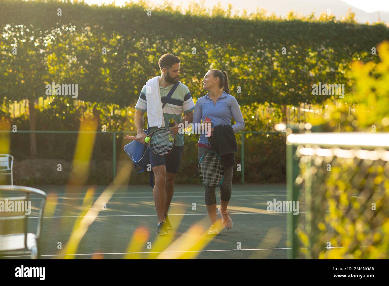 Image of happy caucasian couple walking with rackets on tennis court ...