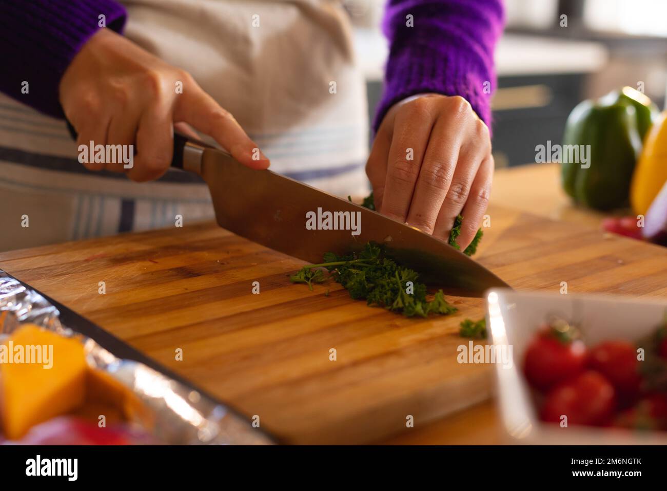 Midsection of caucasian woman standing in kitchen chopping fresh herbs ...