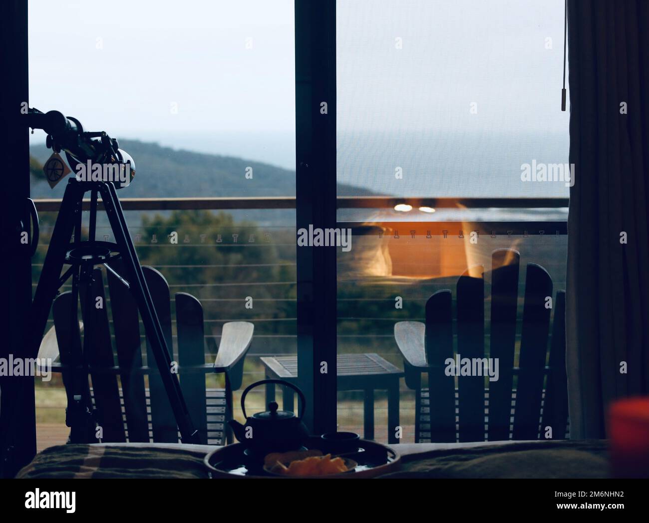 The modern telescope near the glass window with chairs in the balcony ...