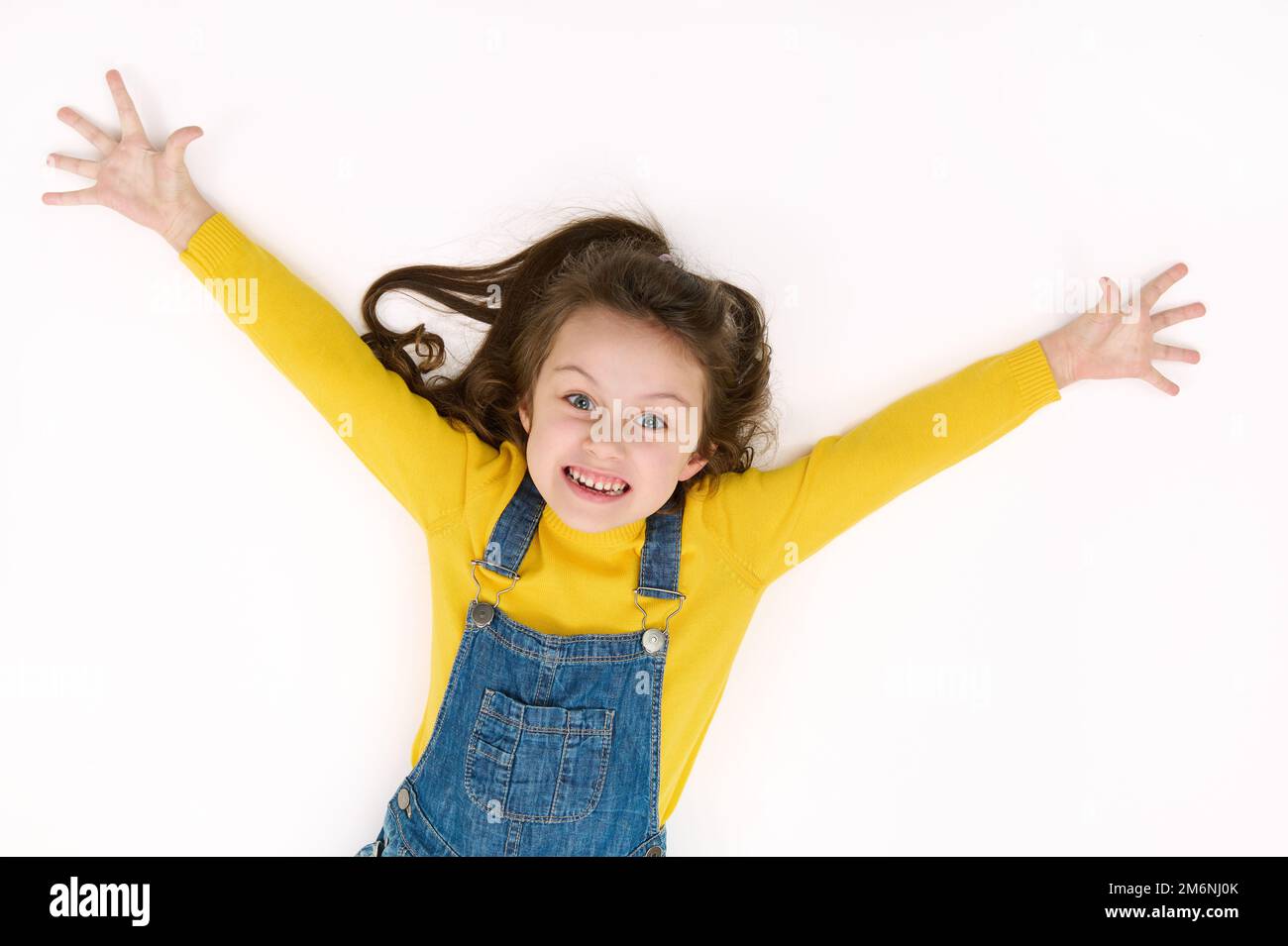 Adorable little child girl with outstretched arms, making faces ...
