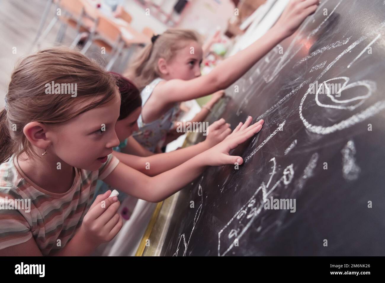 Children write and draw on the blackboard in elementary school while ...