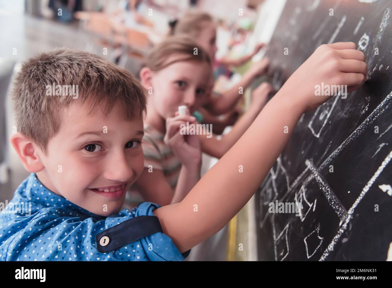 Children write and draw on the blackboard in elementary school while ...