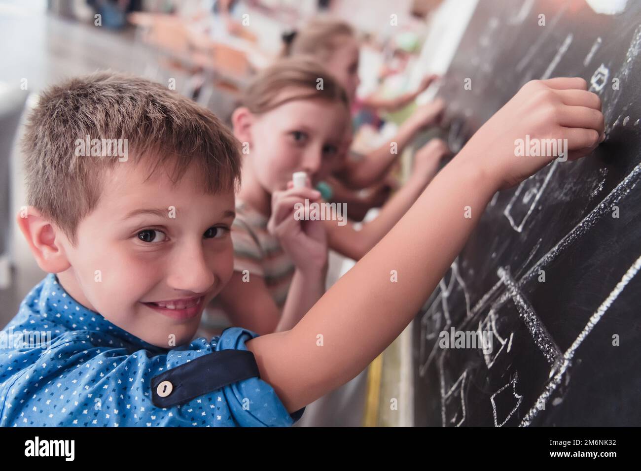 Children write and draw on the blackboard in elementary school while ...