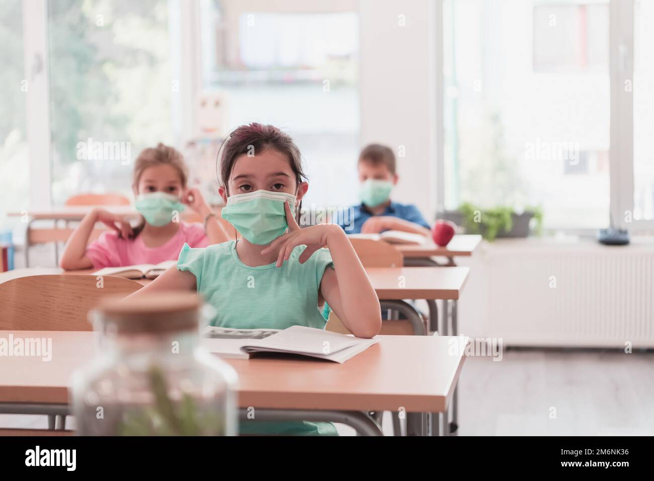 Multiracial group of kids wearing face masks working at class, writing ...