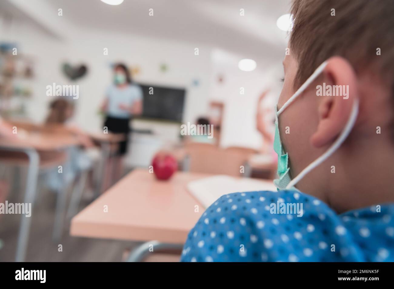 Multiracial group of kids wearing face masks working at class, writing ...