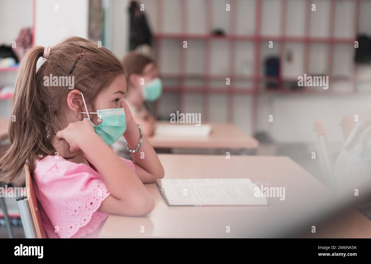 Multiracial group of kids wearing face masks working at class, writing ...