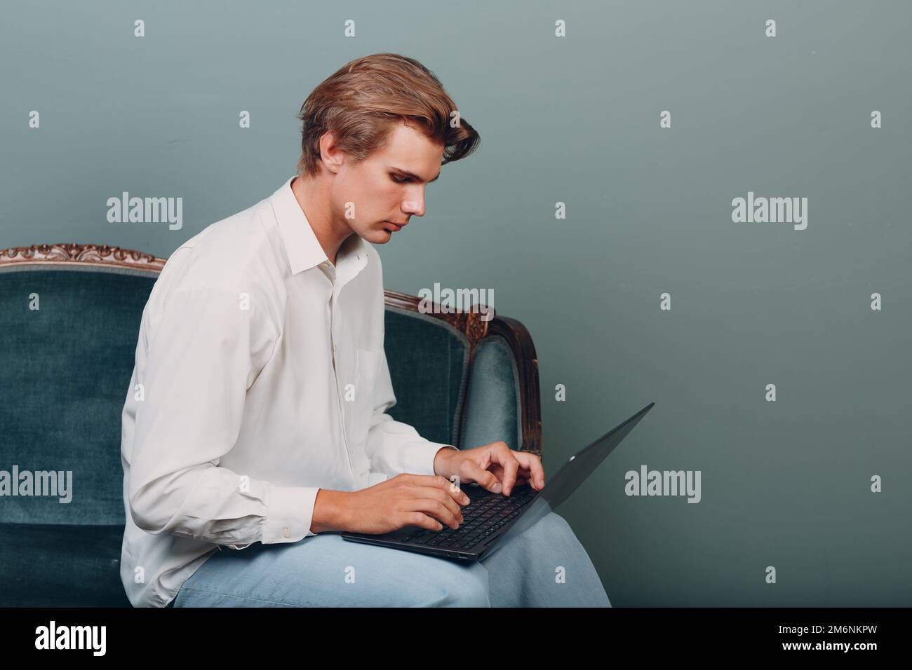 Portrait young man sitting with laptop at studio Stock Photo - Alamy