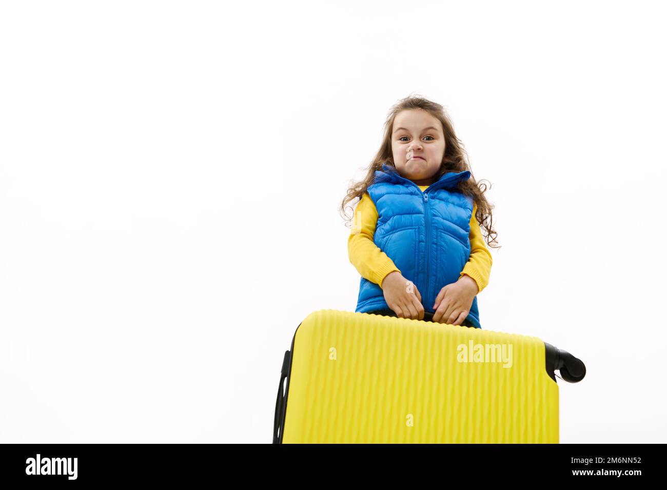 Caucasian mischievous child girl in blue jacket, going for vacations ...
