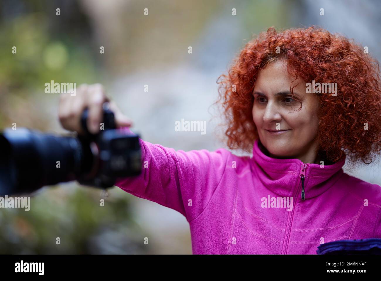 portrait of a woman with curly hair taking photos with a digital camera ...
