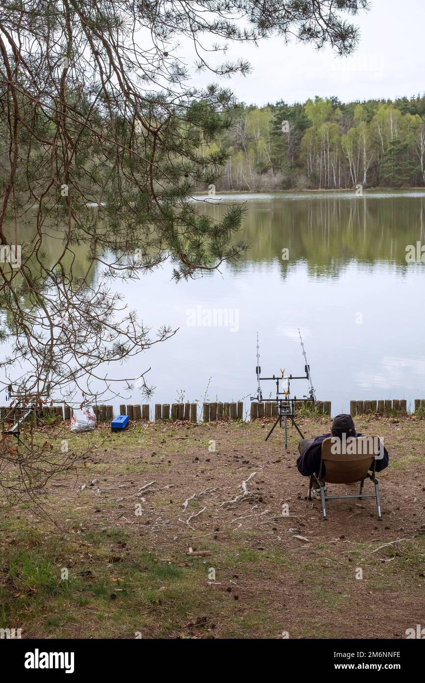 Fisherman sitting by a lake in front of his two fishing rods Stock ...