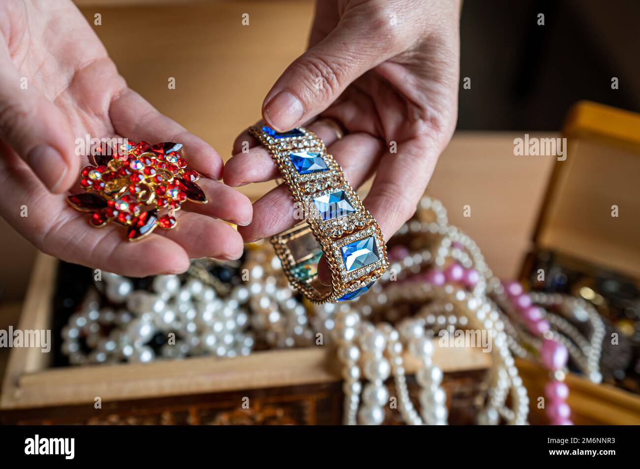 Wooden treasure chest with valuables. A woman holds beads, necklaces ...