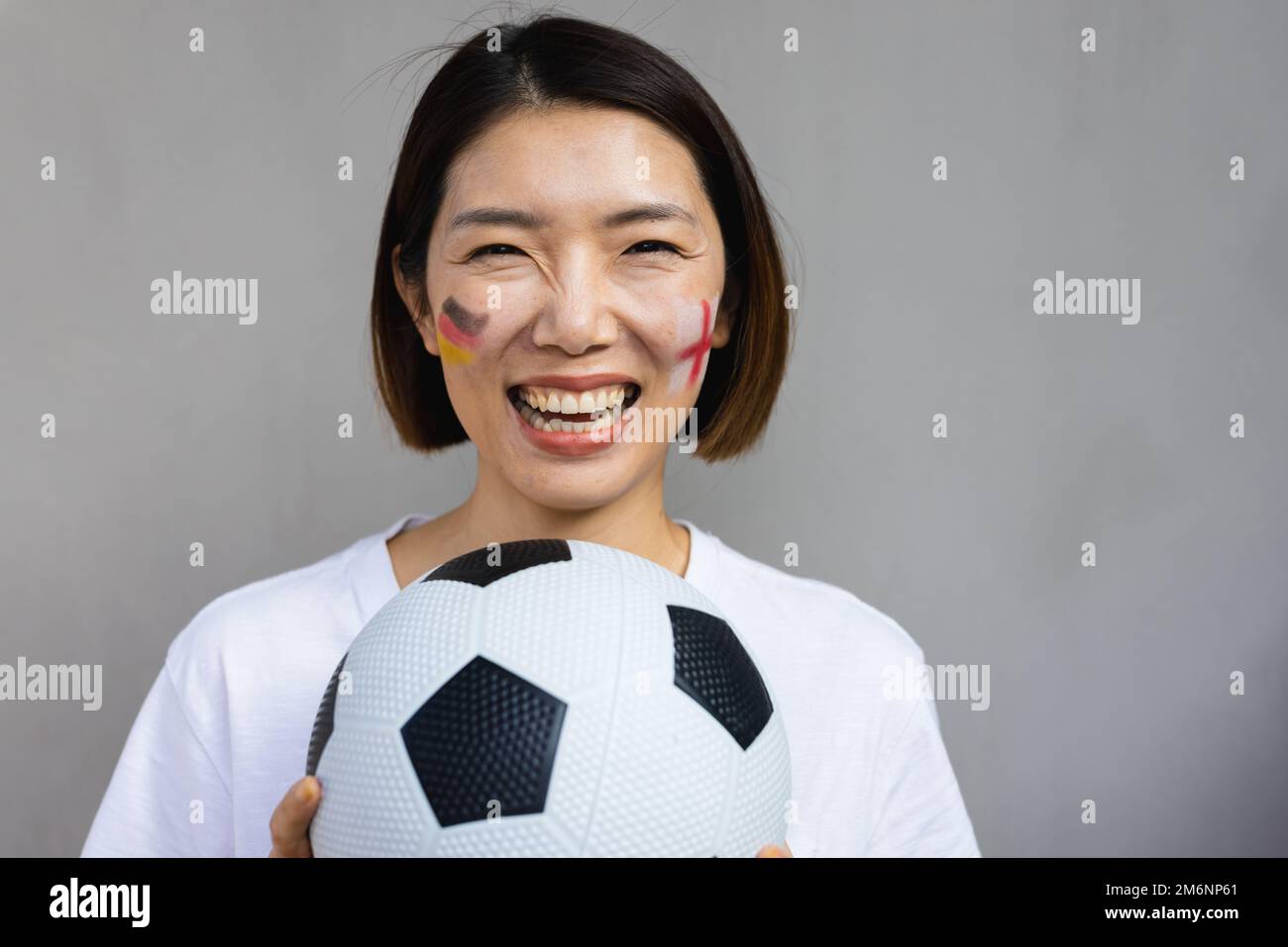 Portrait of happy asian woman with football and flags of germany and ...