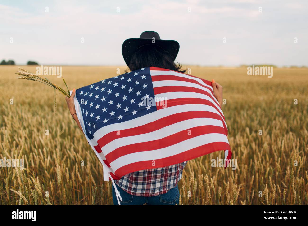 Woman farmer wearing cowboy hat, plaid shirt and jeans with american ...