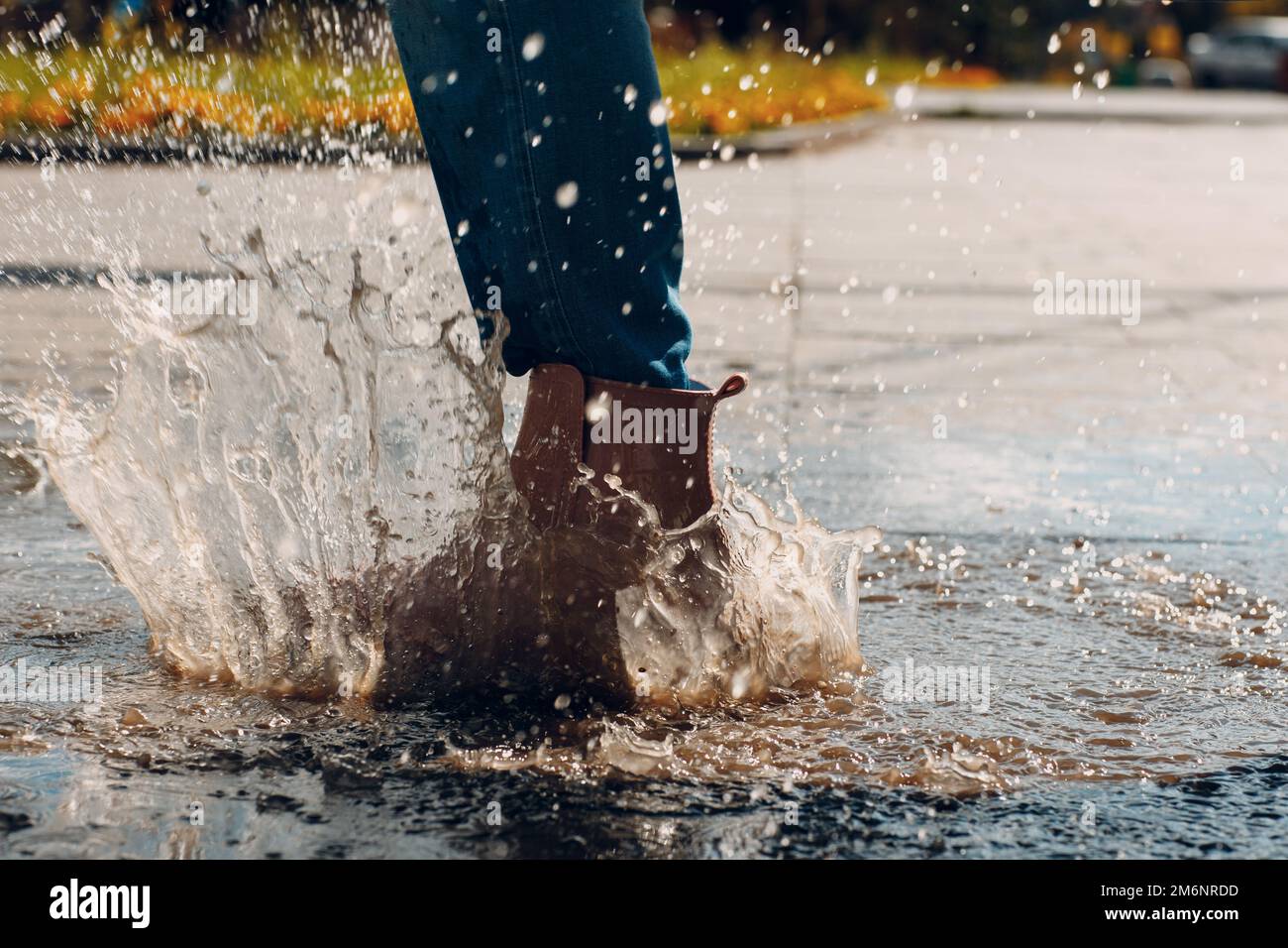 Woman wearing rain rubber boots walking running and jumping into puddle ...