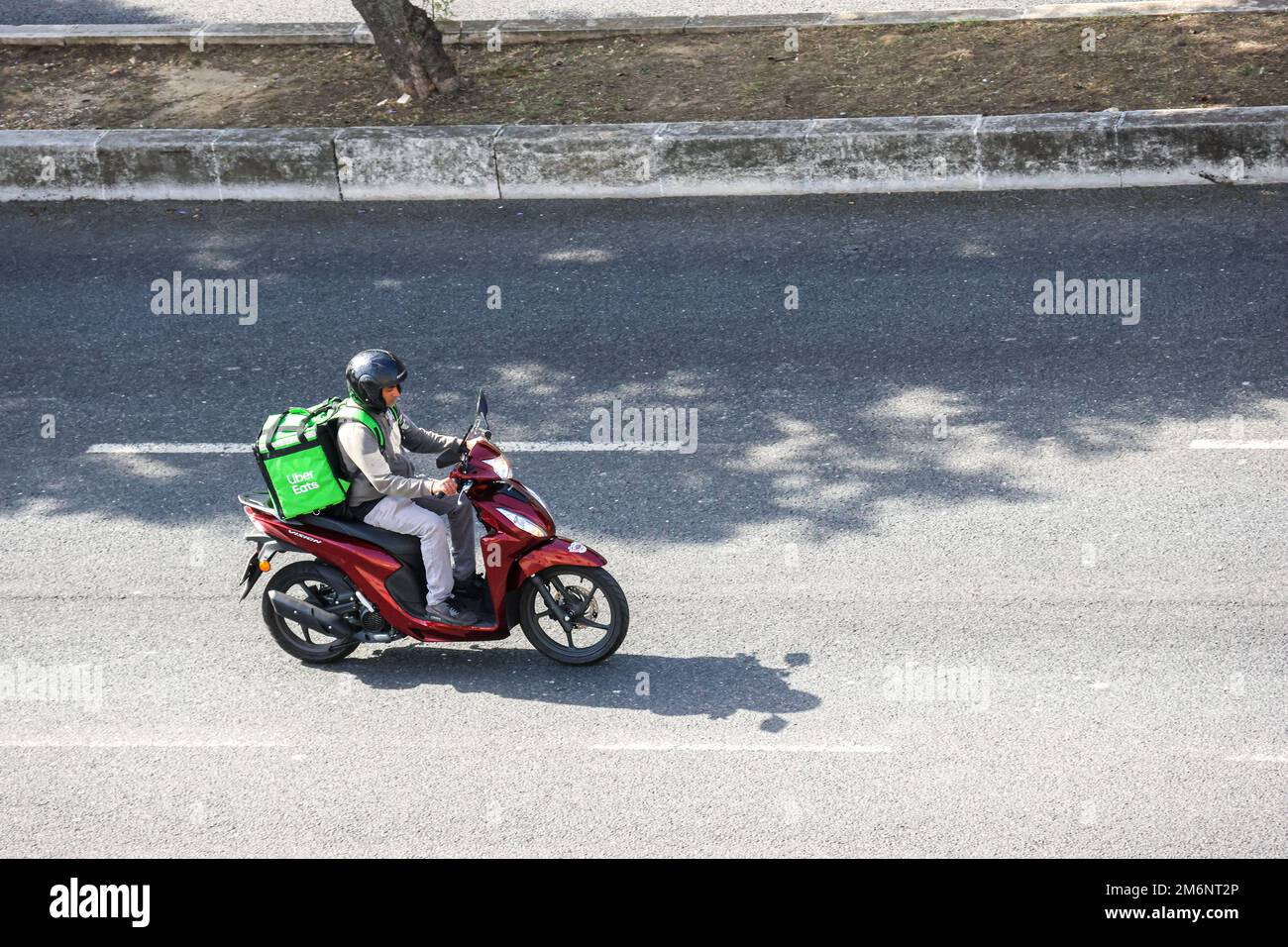 A courier of the Uber Eats delivery company driving on the streets of ...