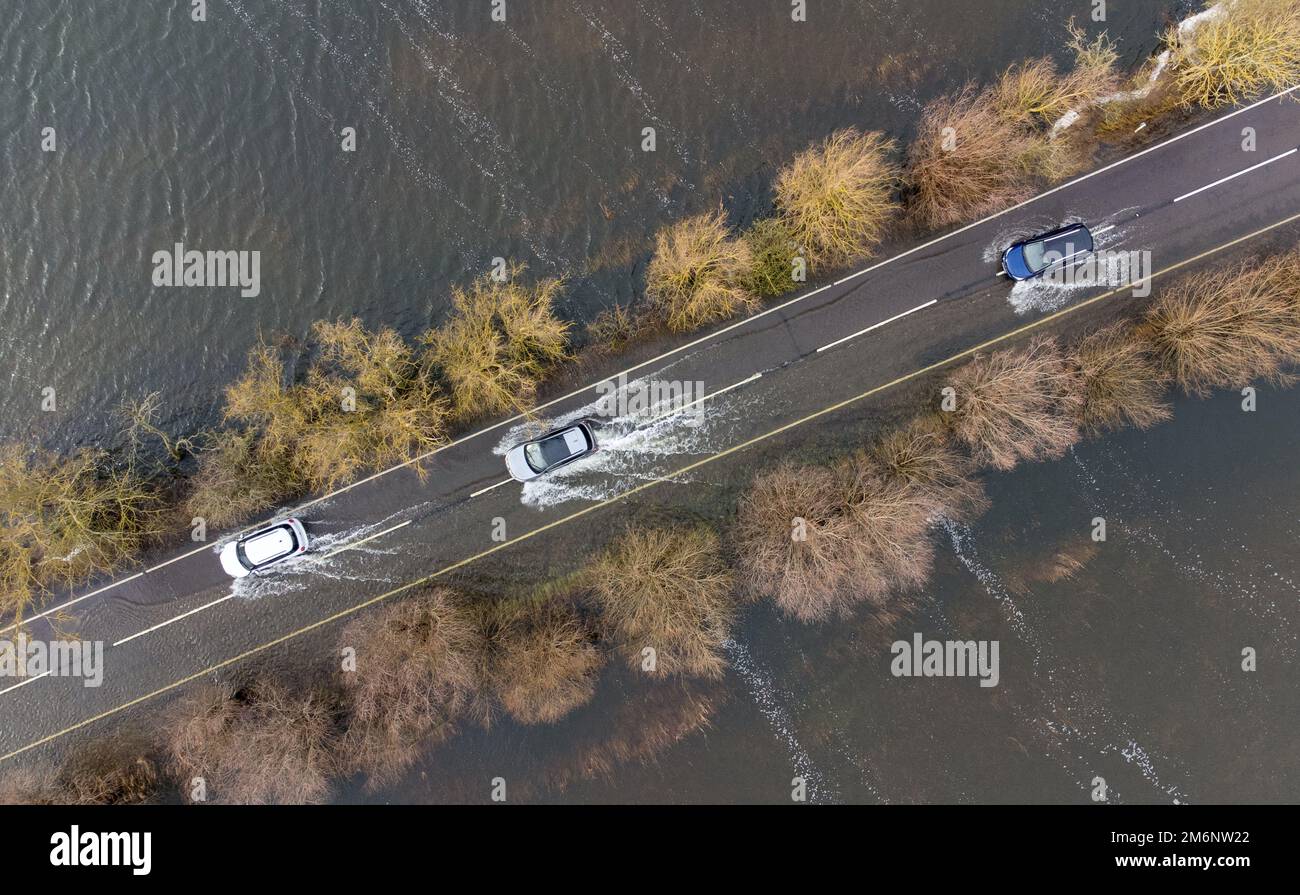 Cars make their way along the flooded A1101 in Welney in Norfolk, where ...