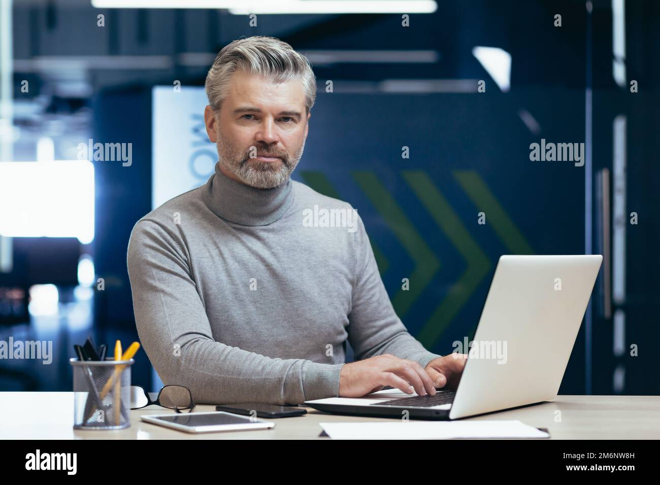 Portrait of serious gray haired boss, man looking at camera thinking ...