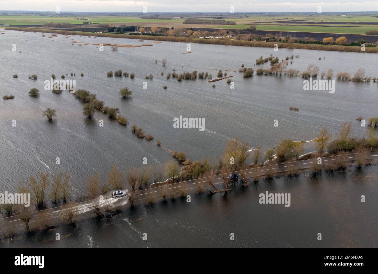 Cars make their way along the flooded A1101 in Welney in Norfolk, where ...