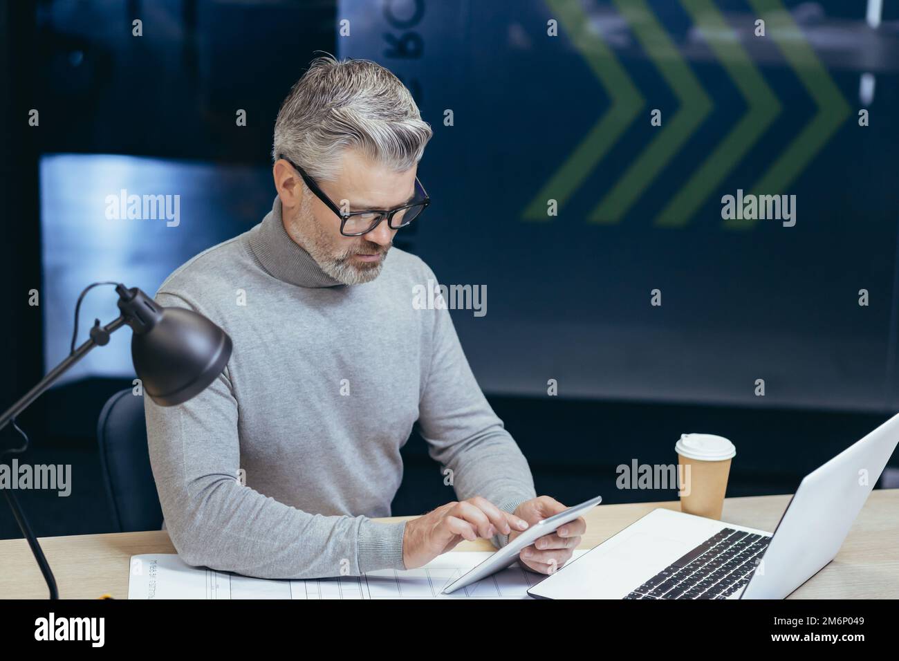 Serious thinking gray-haired businessman working inside office with ...