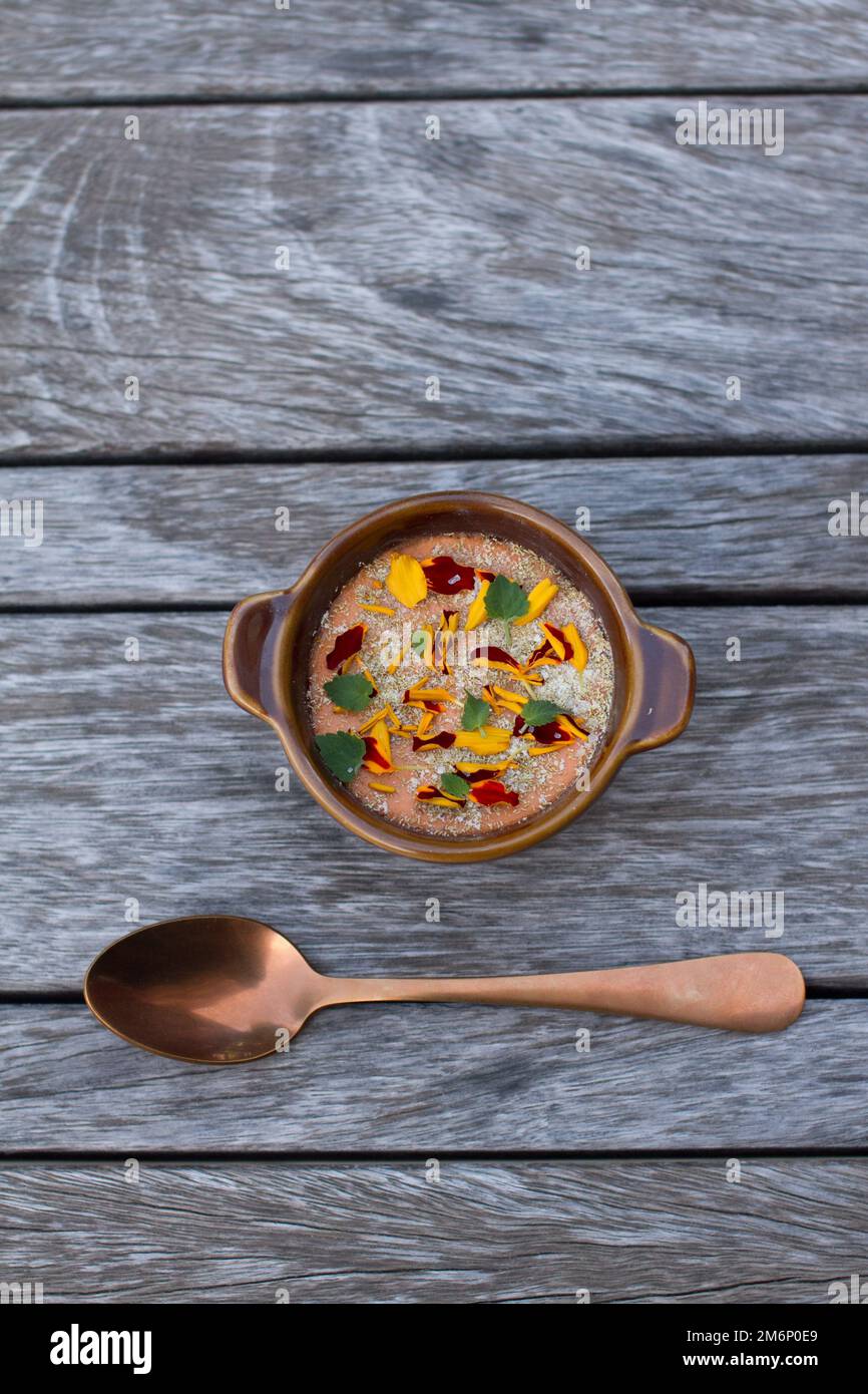 A top view of a bowl of cream soup garnished with edible flowers on a ...