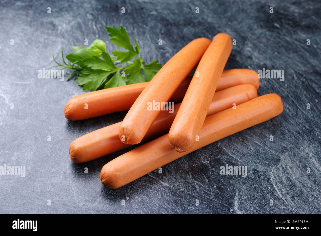 Traditional raw German bockwurst offered as close-up on a gray board ...