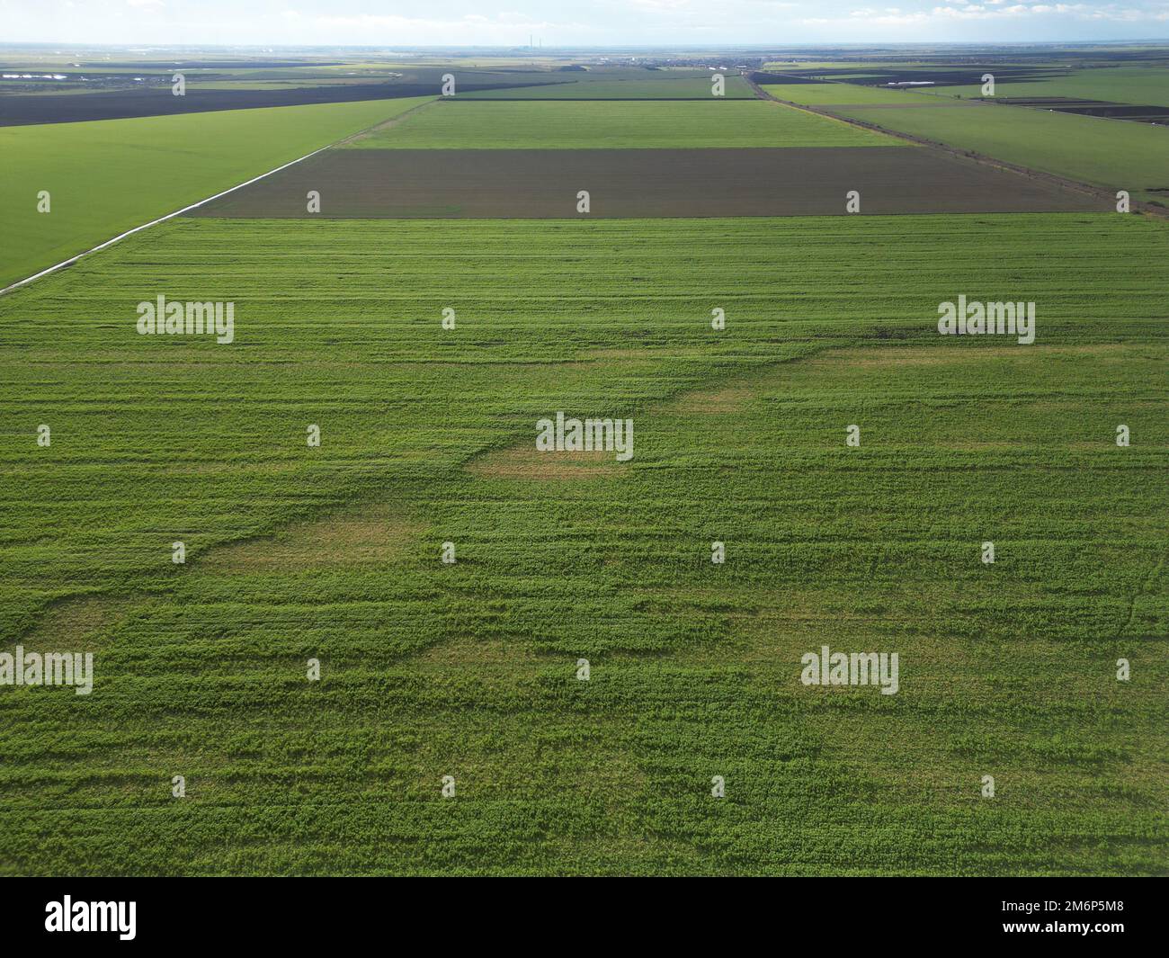 A high angle of farm green fields with a cloudy sky in the background ...