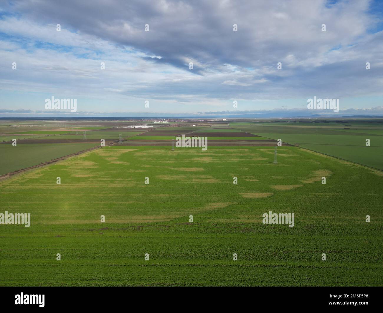 A high angle of farm green fields with a cloudy sky in the background ...