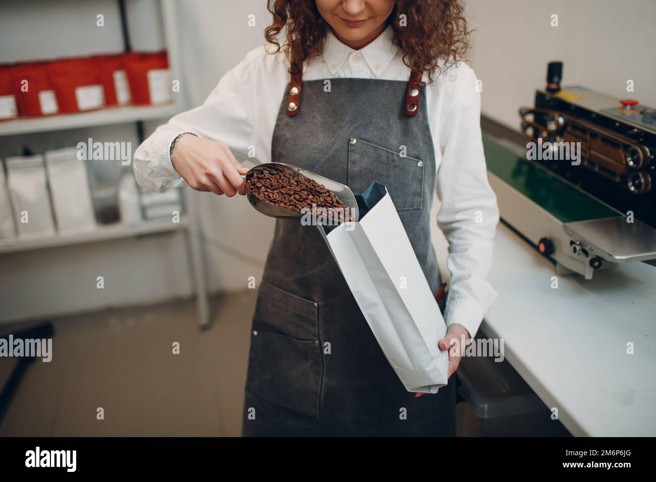 Fresh roasted coffee beans young worker woman packing machine in vacuum ...