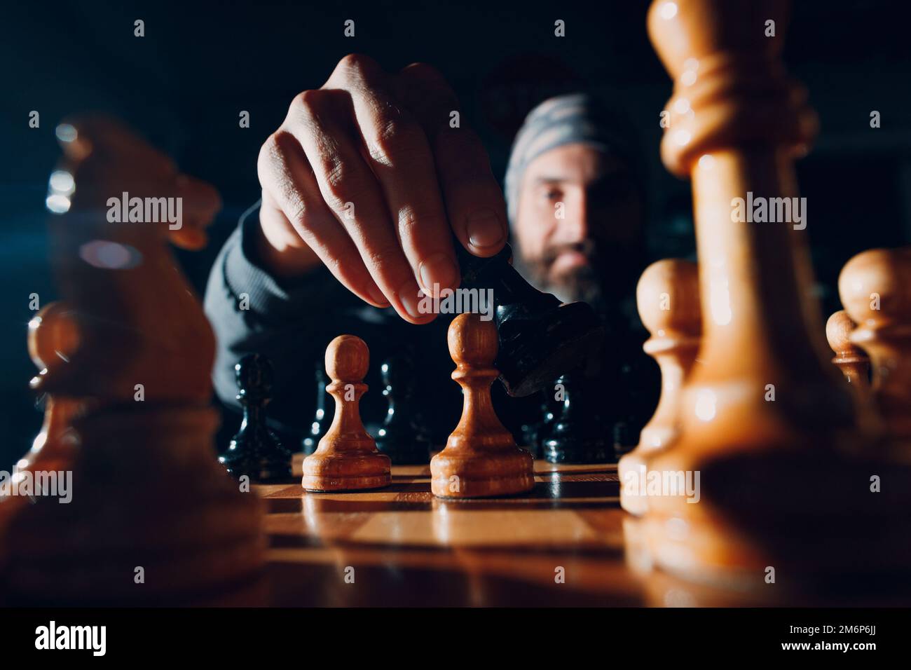 Young adult handsome man playing chess in dark with side lit Stock ...