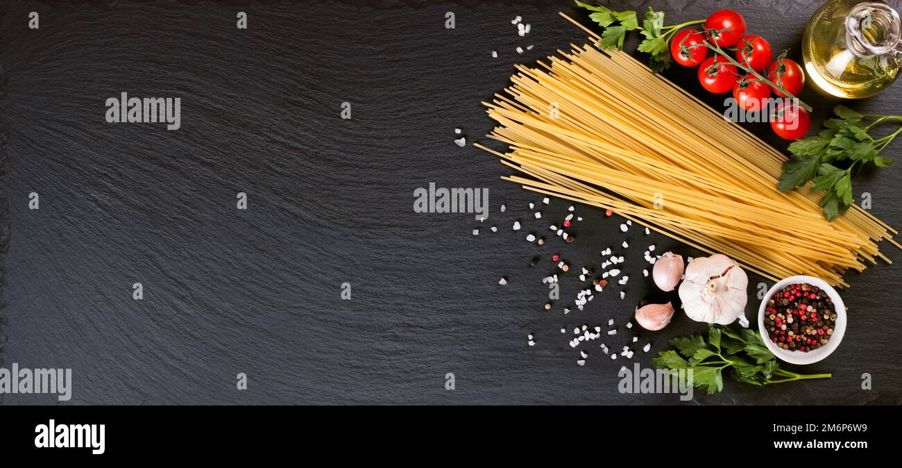 Pasta, spaghetti and cooking ingridients on black slate surface ...