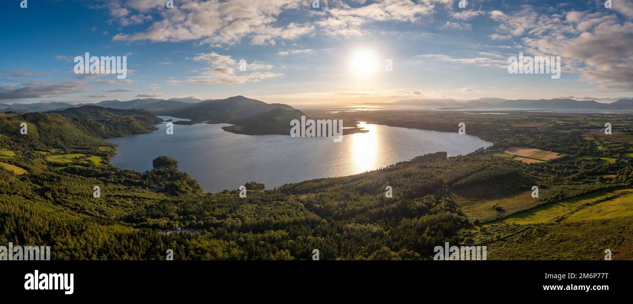 An aerial panorama of Caragh Lake in County Kerry with the sun setting ...