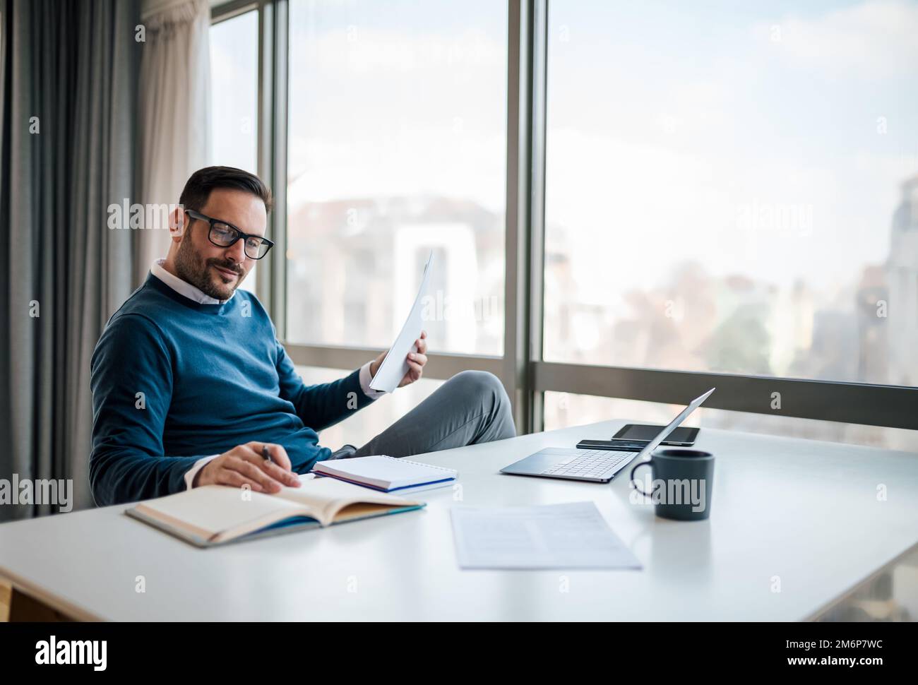 Calm, casual young adult businessman, checking his notes, making sure ...