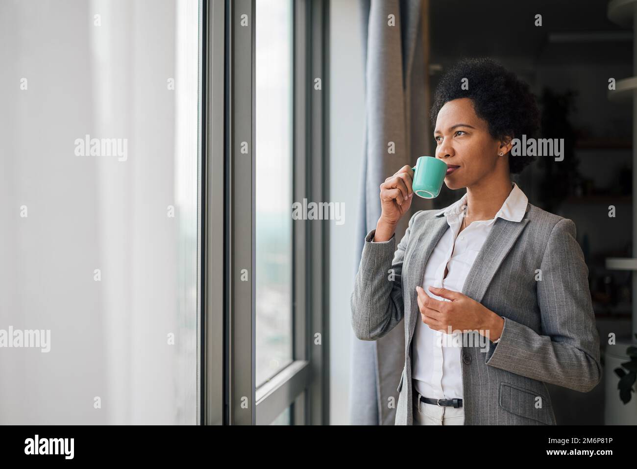 Elegant adult businesswoman, taking a sip of her drink, looking through ...