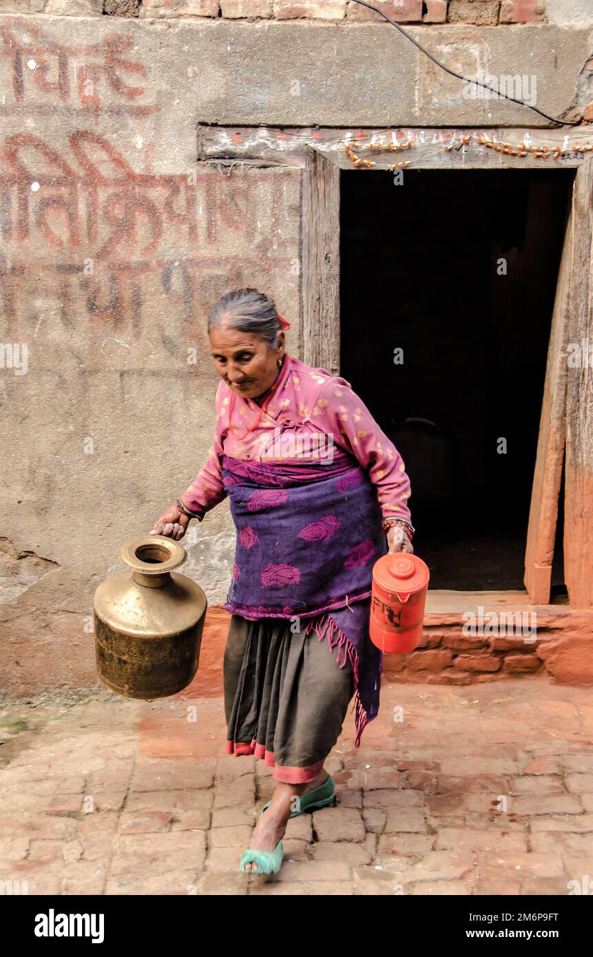 Faces of Nepal: Elderly Woman Carries Water Jar Stock Photo - Alamy