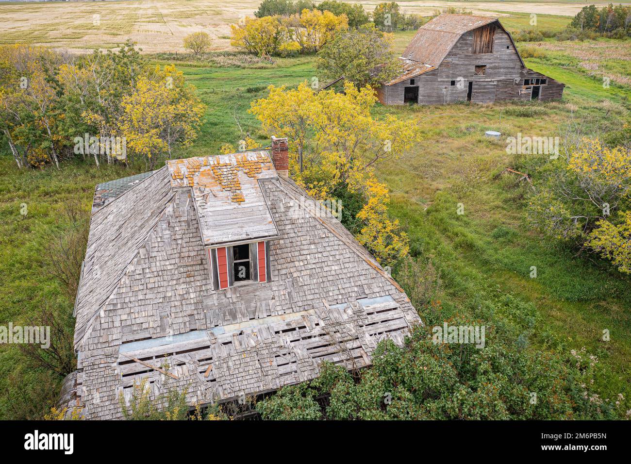 An aerial of an old abandoned wooden homestead with the field in the ...