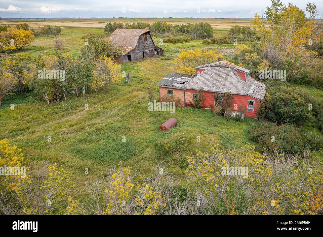 An aerial of an old abandoned wooden homestead with the field in the ...