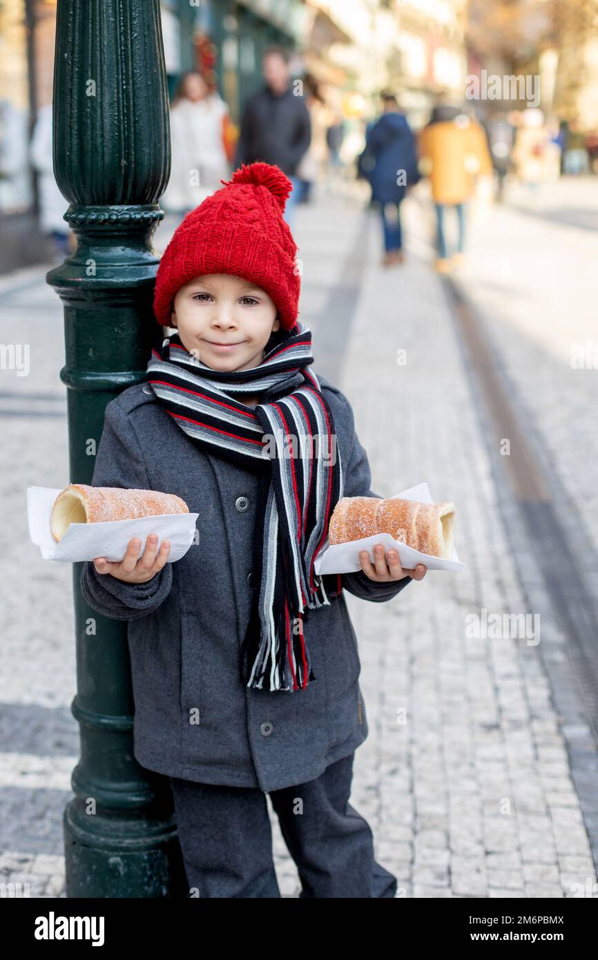 Child in Prague on Christmas, cute boy, eating traditional czech pastry ...