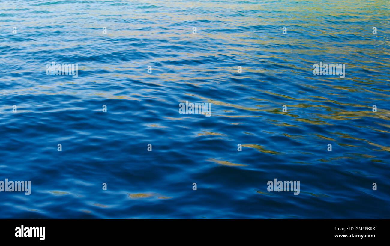 Waveless, calm sea at sunset. Pale sun rays reflecting off the sea ...