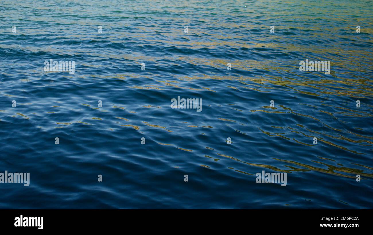 Waveless, calm sea at sunset. Pale sun rays reflecting off the sea ...
