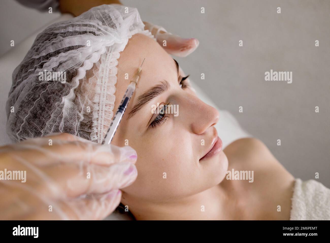 A young woman receives an injection of anti-aging botox filler in the ...