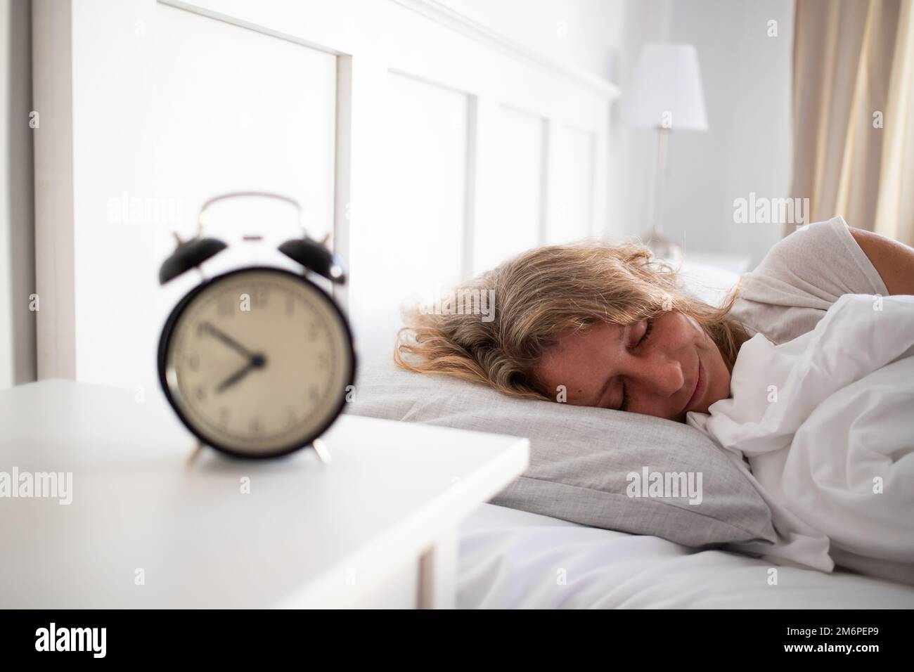 Alarm clock and woman sleeping in bed sleep quality Stock Photo - Alamy