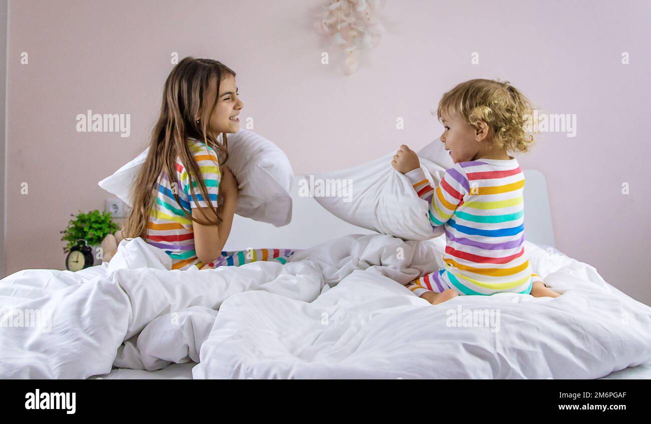 Children hitting pillows in bed. Selective focus. Kid Stock Photo - Alamy