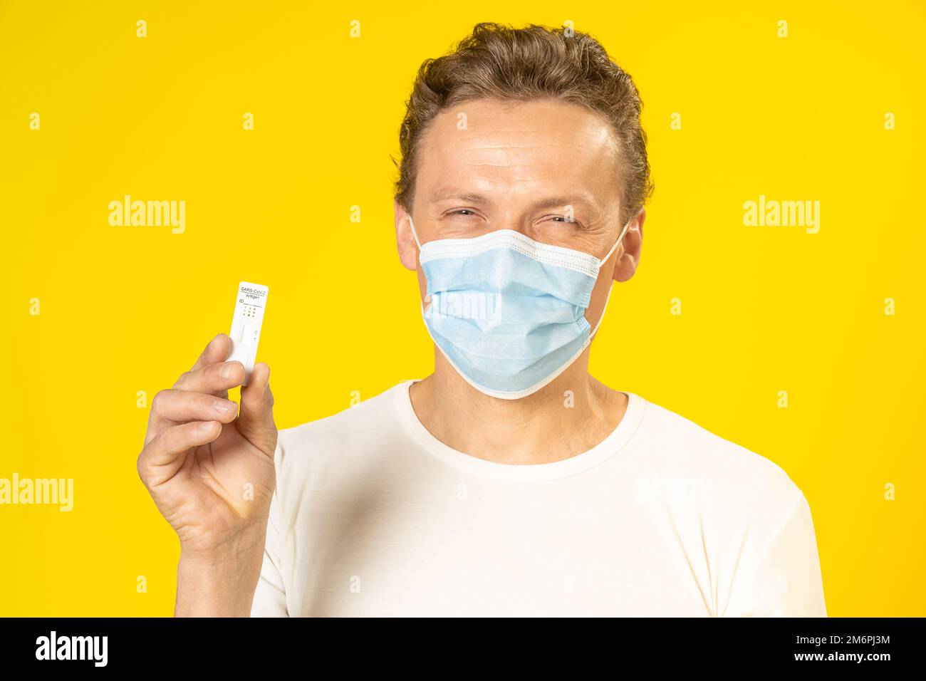 Happy young man showing test in hand wearing medical face mask ...