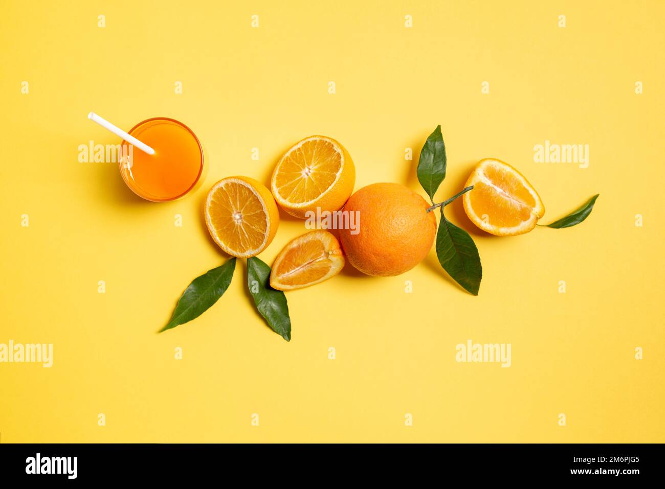 Orange fruit top view with slices and glass of juice on yellow ...