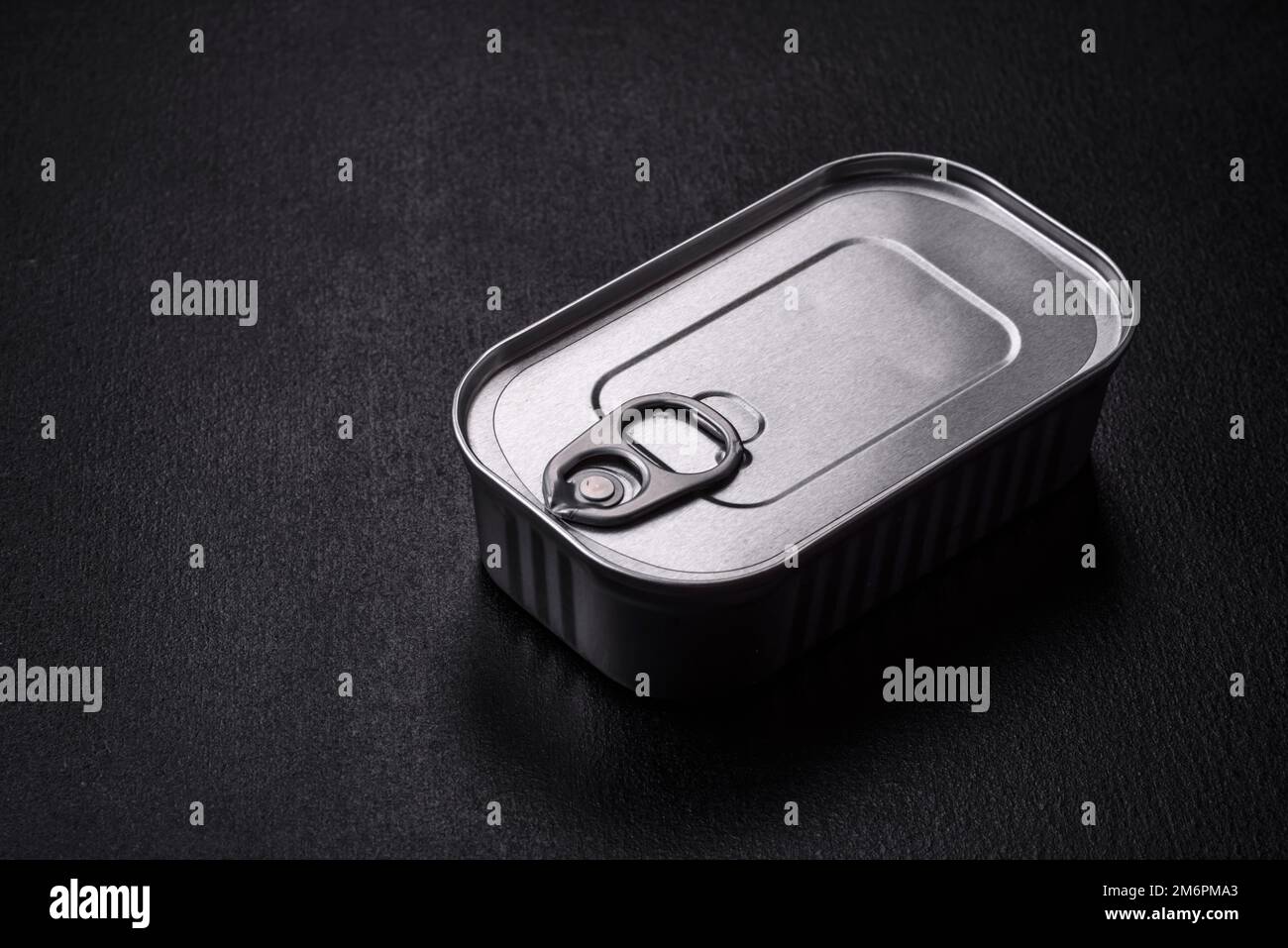 Tin or aluminum rectangular can of canned food with a key on a dark ...