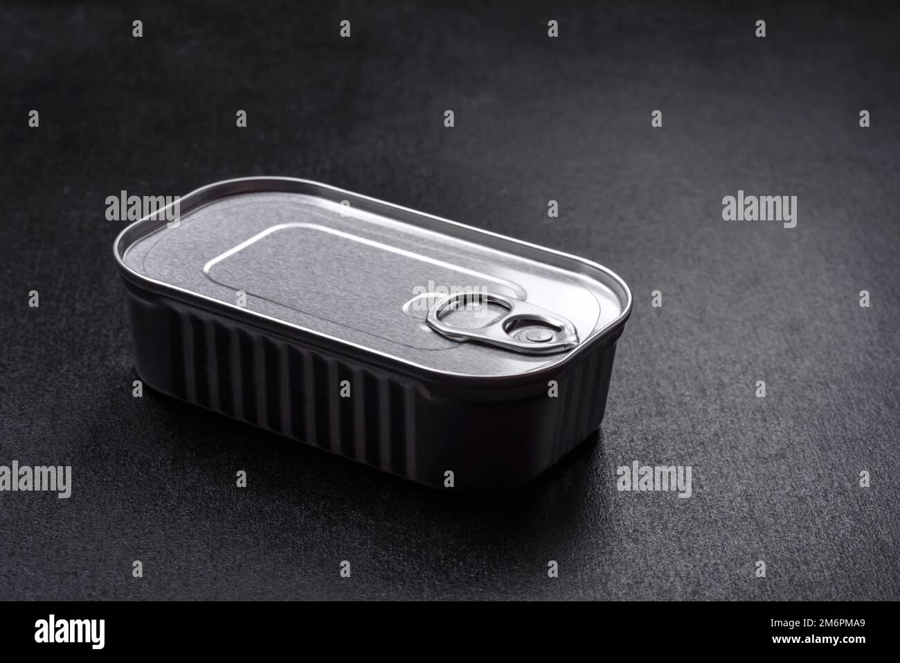 Tin or aluminum rectangular can of canned food with a key on a dark ...