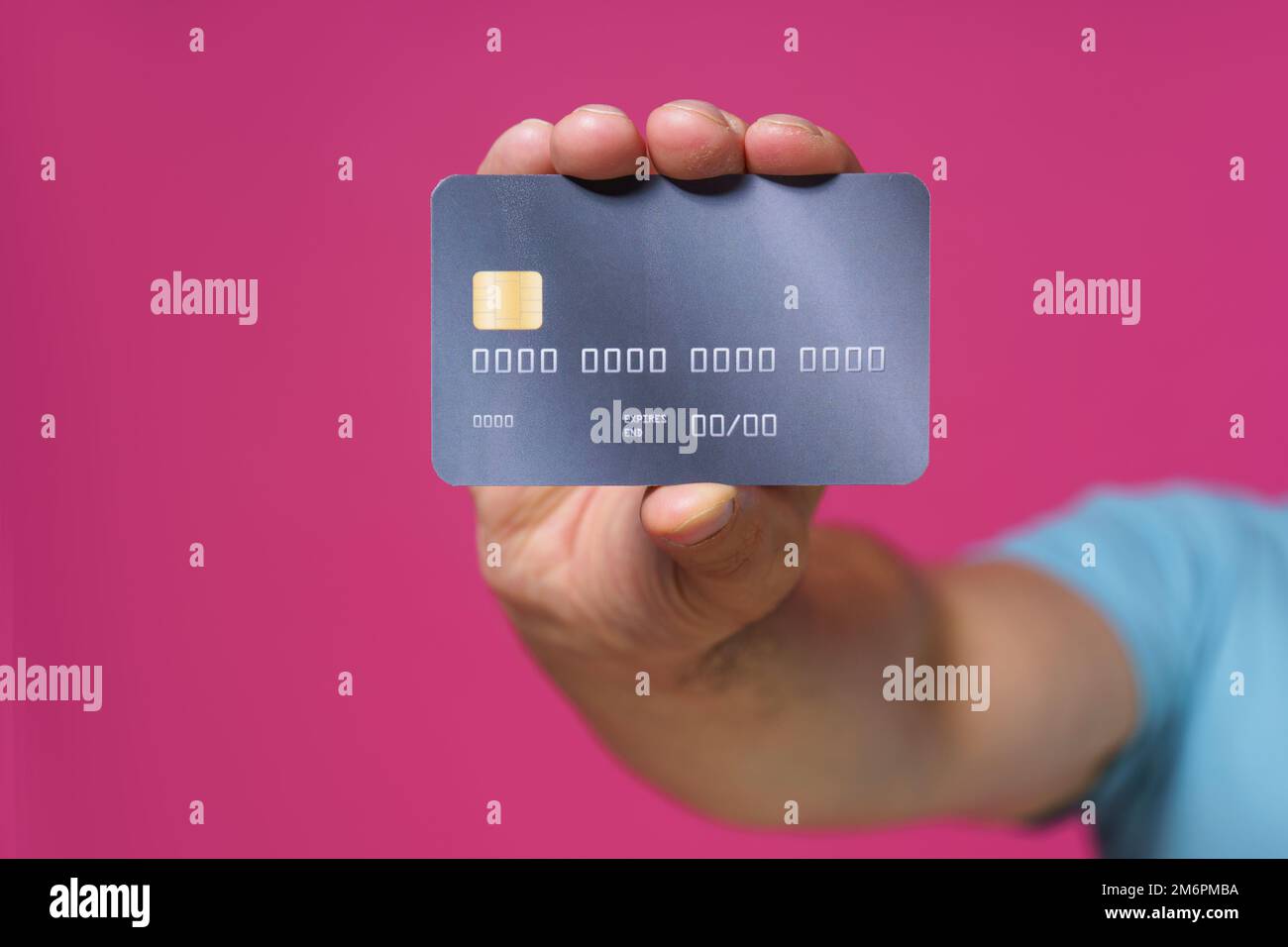 Dark grey-purple debit, credit card in man hand isolated on pink ...