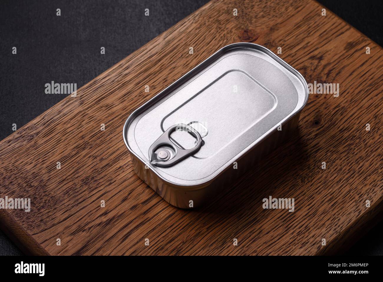 Tin or aluminum rectangular can of canned food with a key on a dark ...